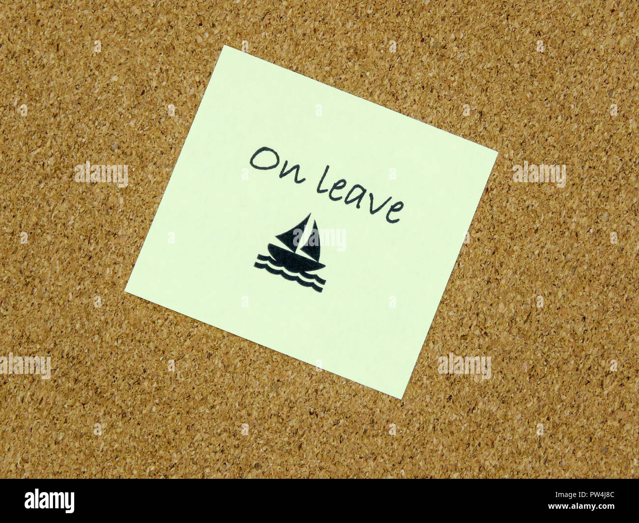 A yellow sticky note with on leave written on it on a cork board ...