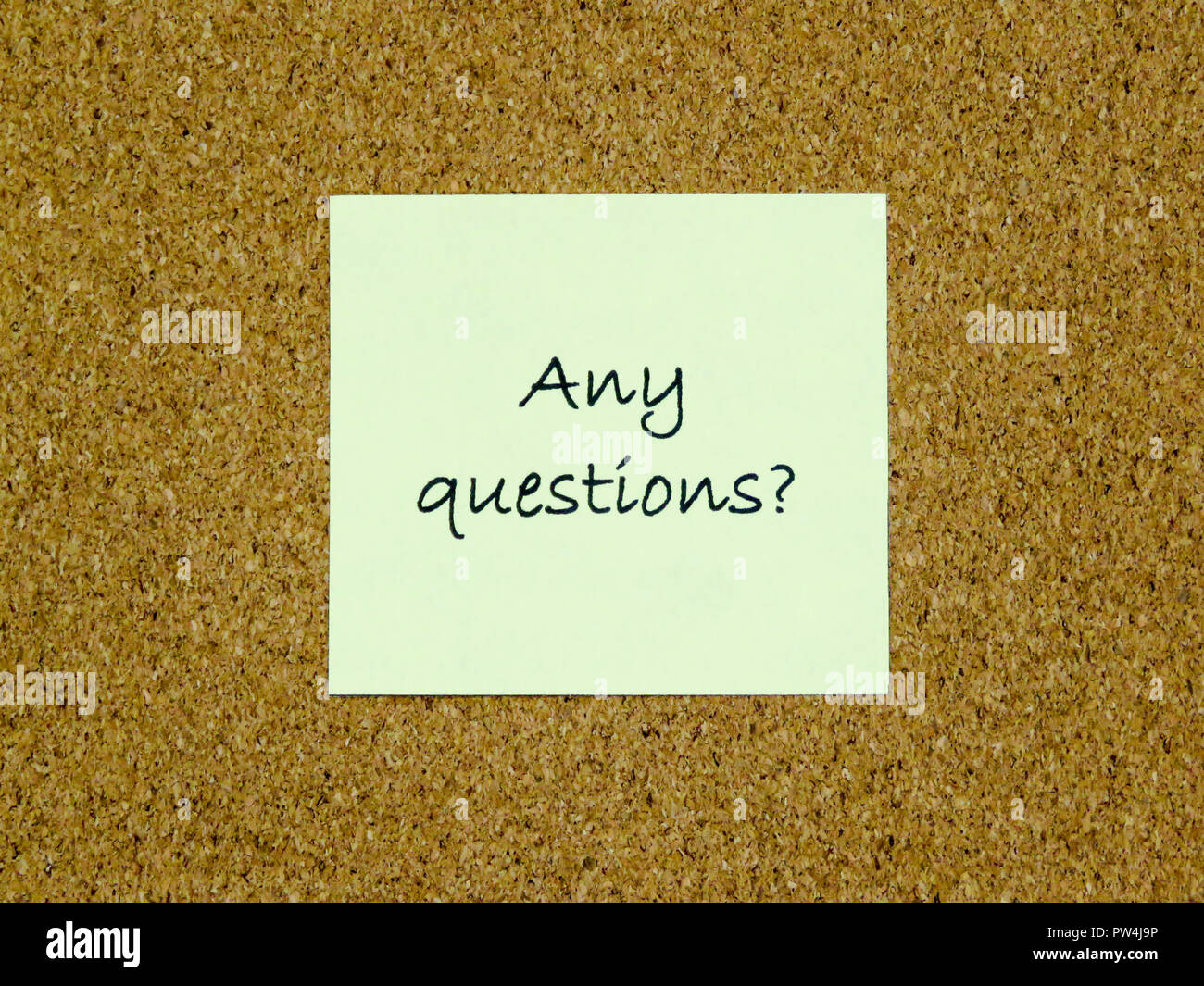 A yellow sticky note with any questions written on it on a cork board ...