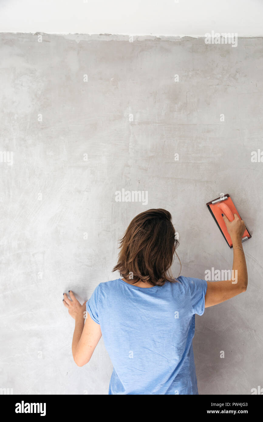 Woman sanding wall with hand sander during renovation Stock Photo - Alamy