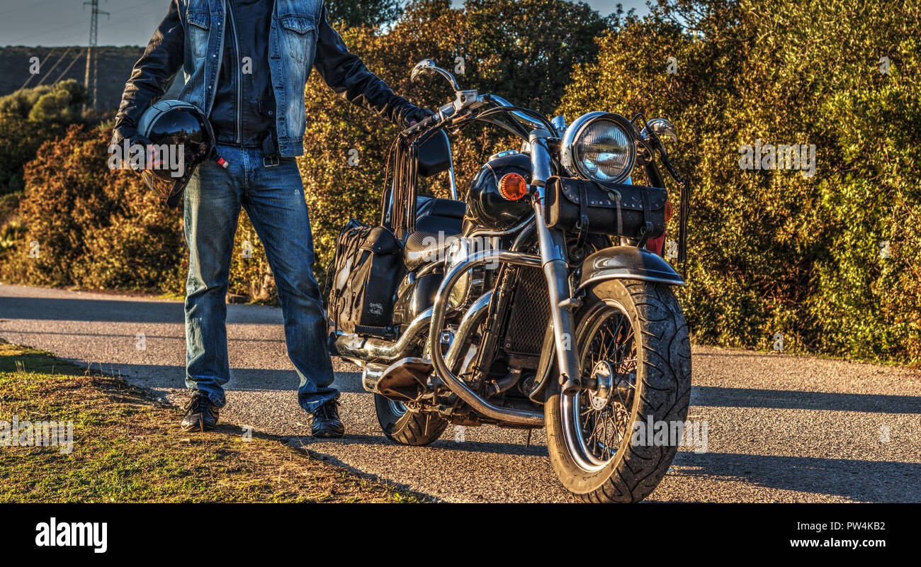 Classic motorcycle and biker on the edge of the road Stock Photo - Alamy