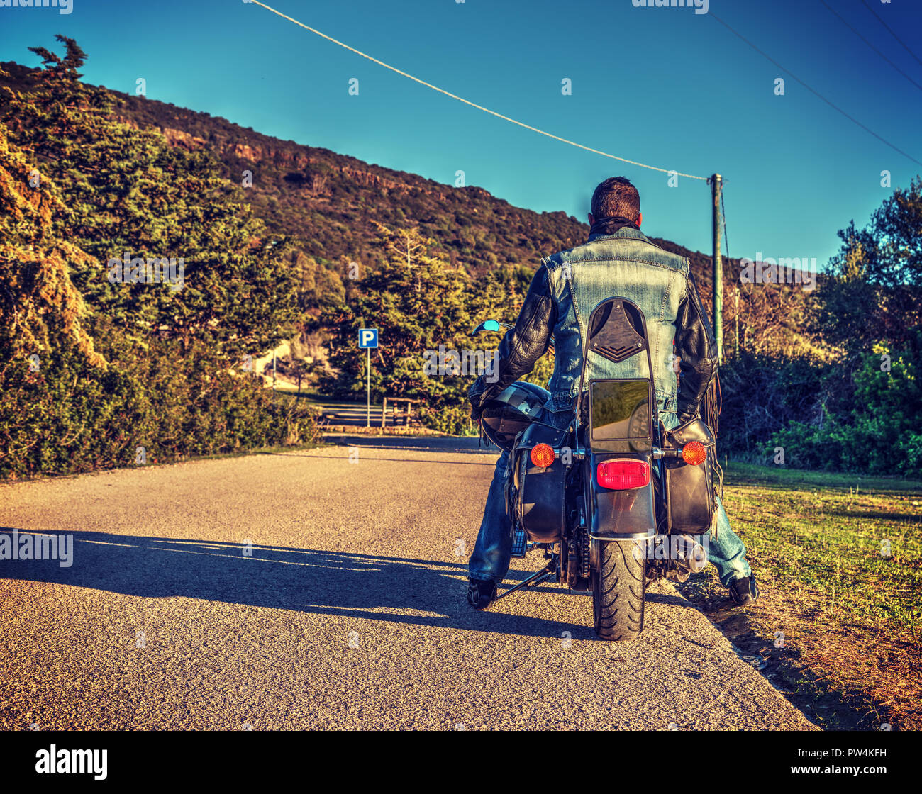 Classic motorcycle and biker on the edge of the road Stock Photo - Alamy