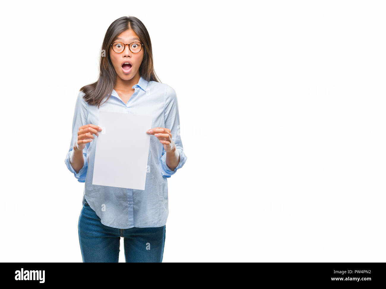 Young asian woman over isolated background holding blank paper scared ...