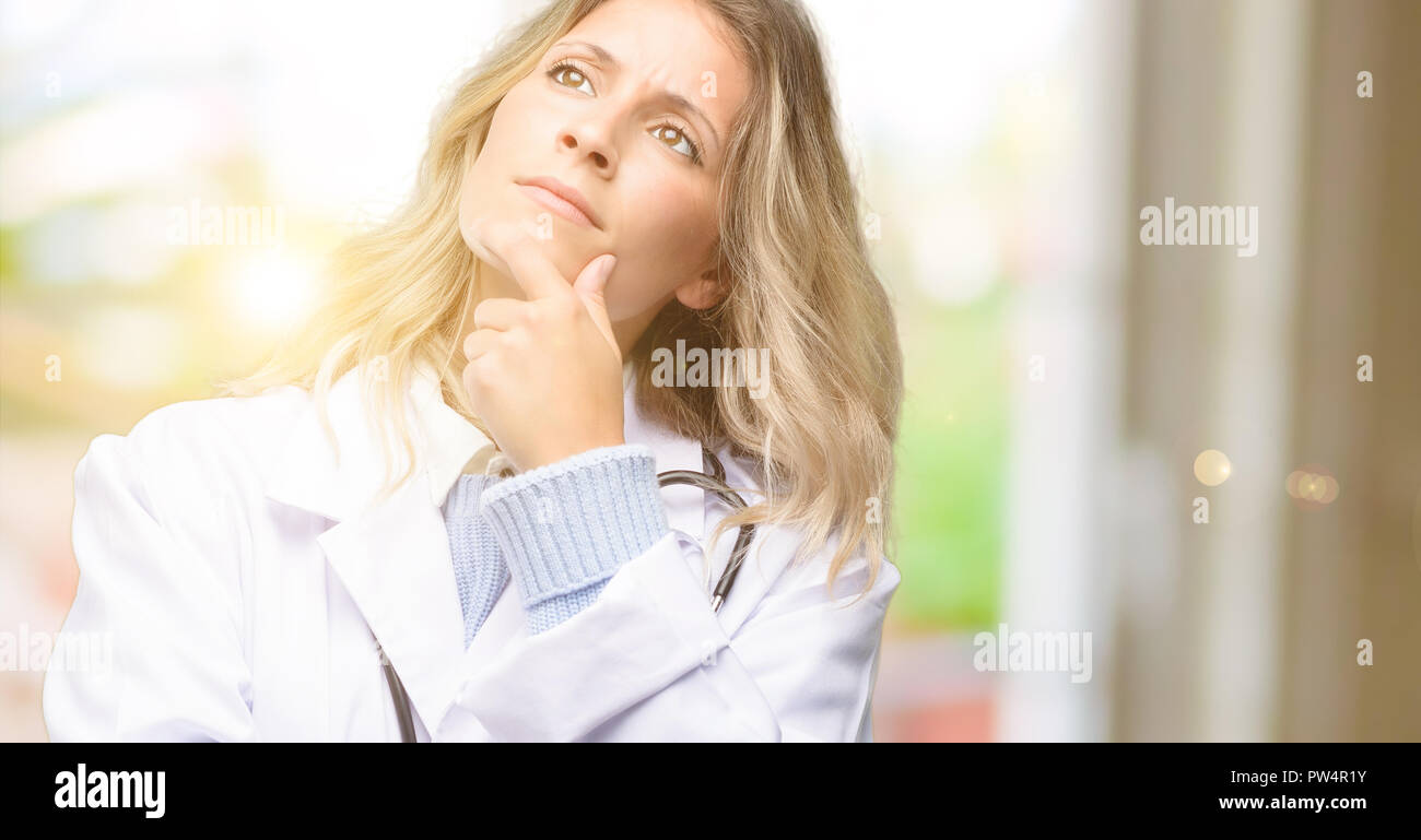 Young doctor woman, medical professional thinking and looking up ...