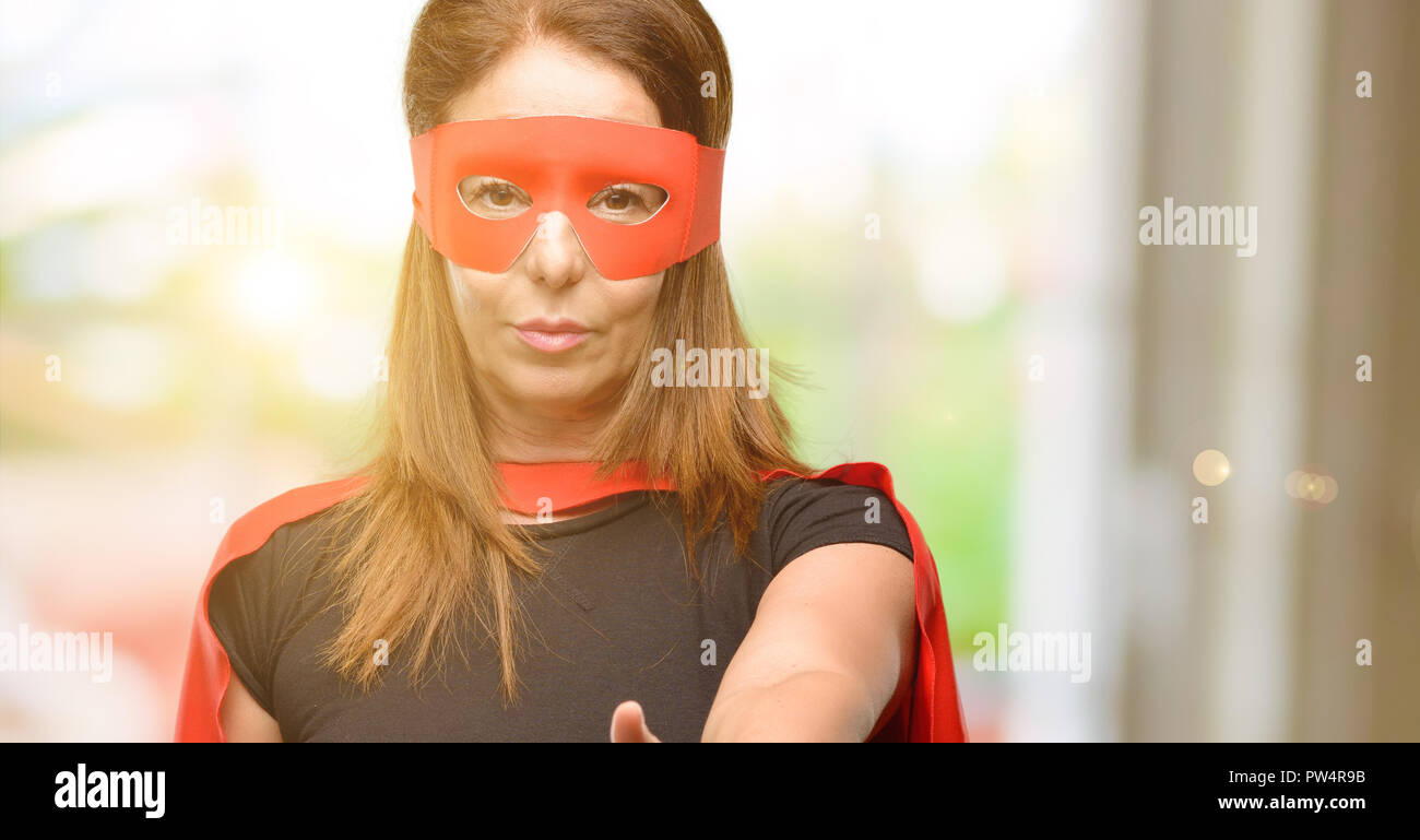 Middle age super hero woman wearing red mask and cape holds hands ...