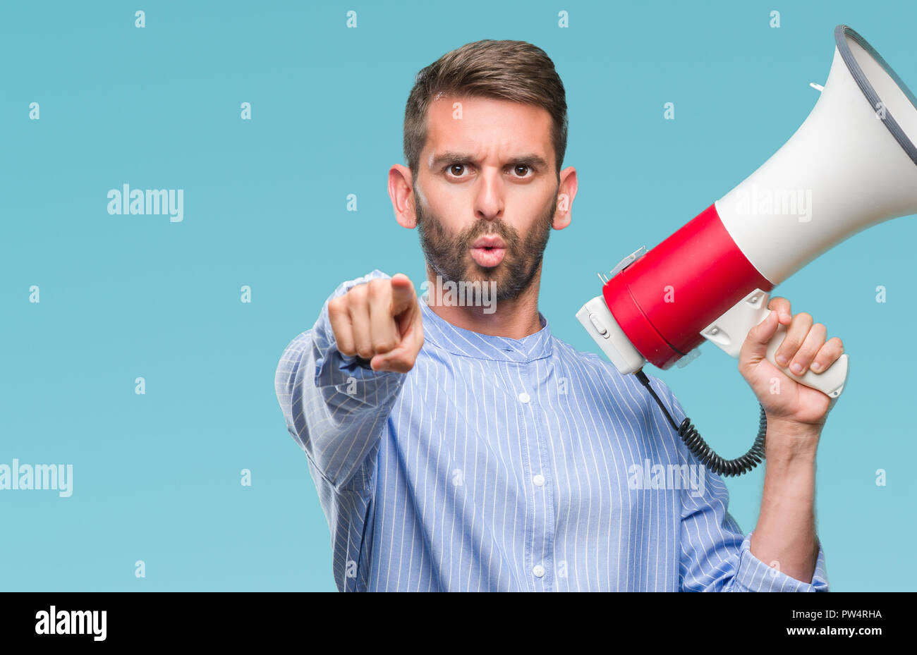 Young handsome man yelling through megaphone over isolated background ...