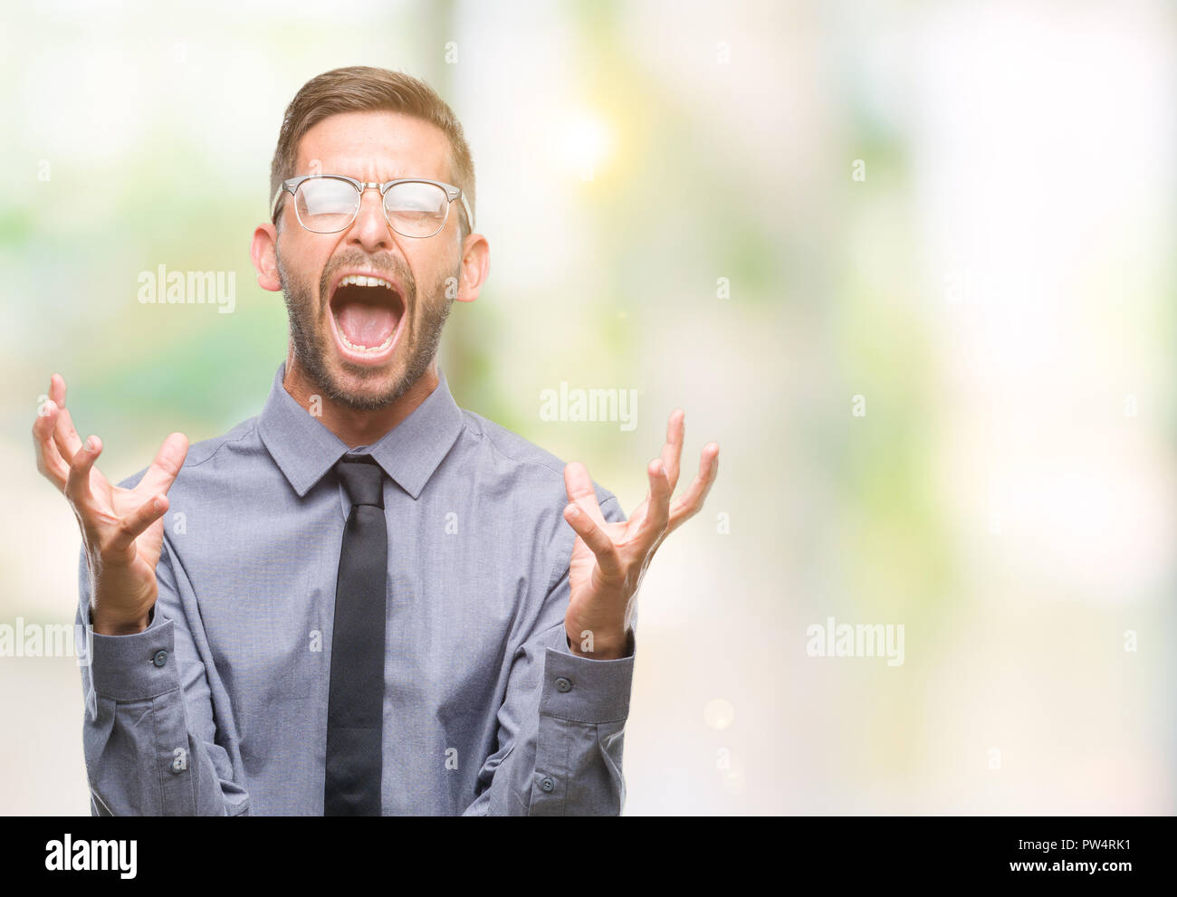 Young handsome business man over isolated background crazy and mad ...
