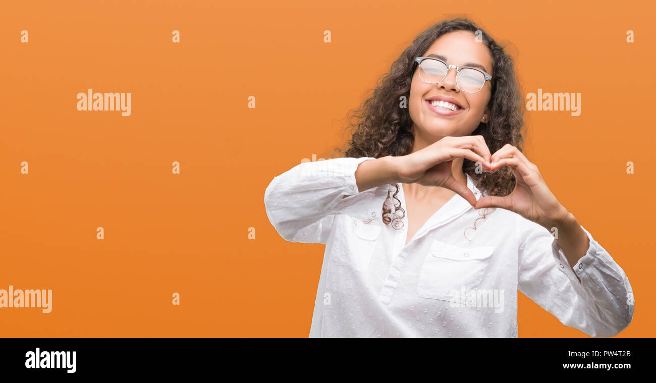 Beautiful young hispanic woman smiling in love showing heart symbol and ...
