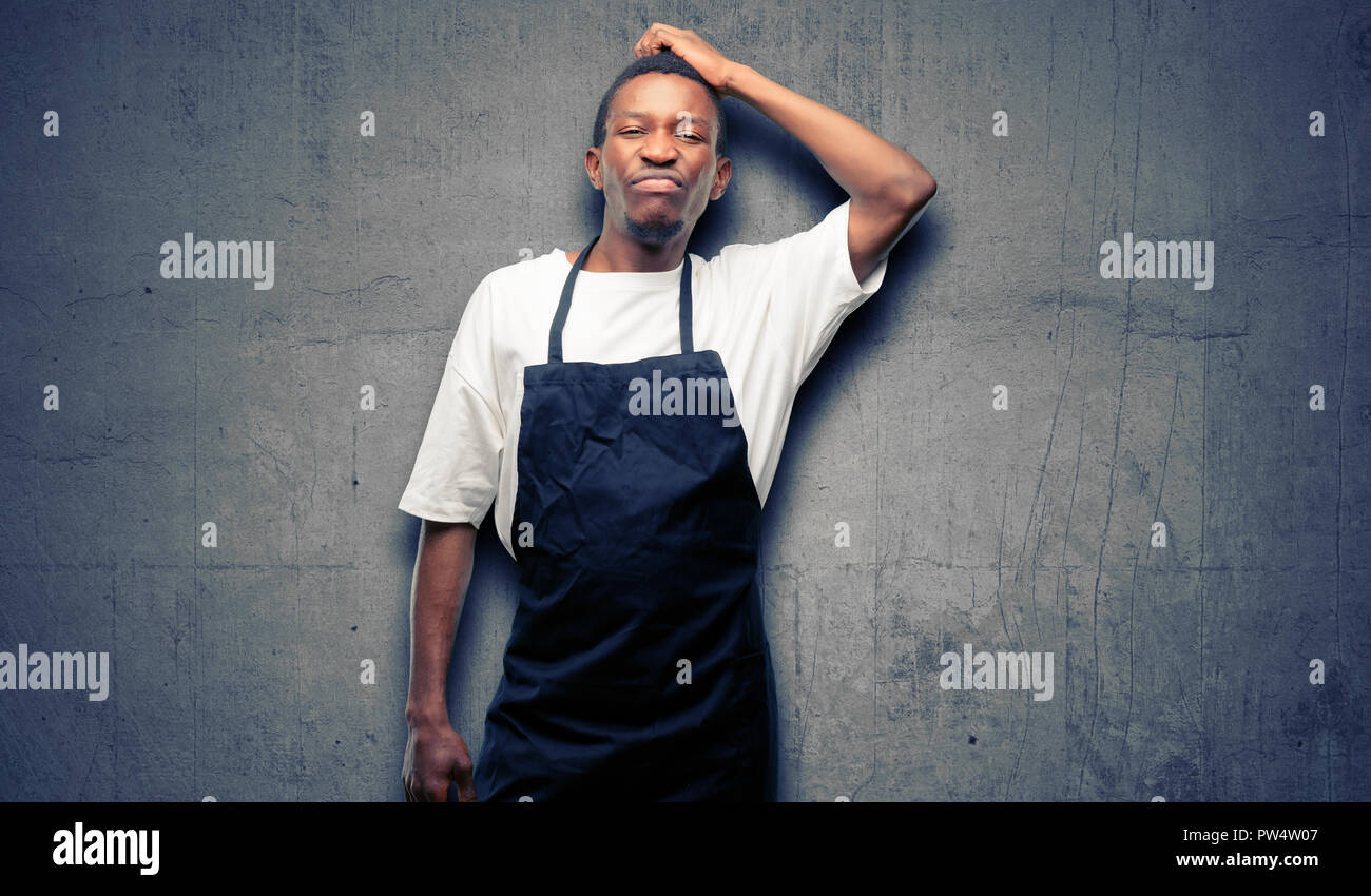 African man shop owner wearing apron doubt expression, confuse and ...