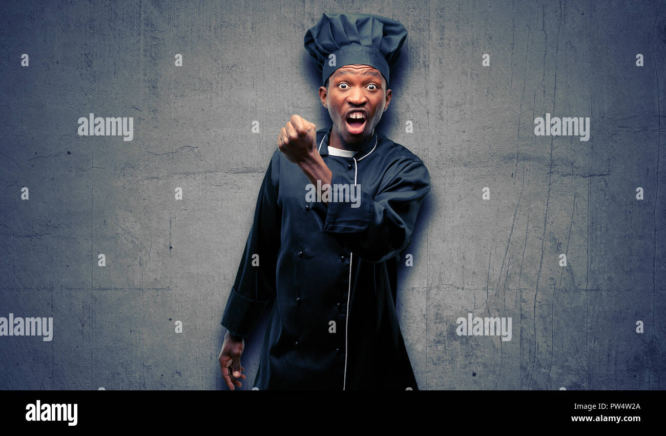 Young black cook wearing chef hat irritated and angry expressing ...