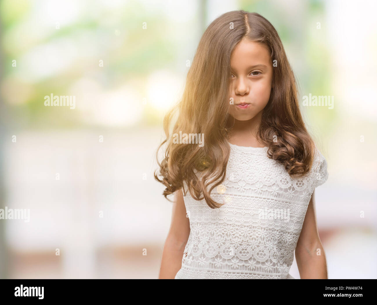 Brunette hispanic girl puffing cheeks with funny face. Mouth inflated ...