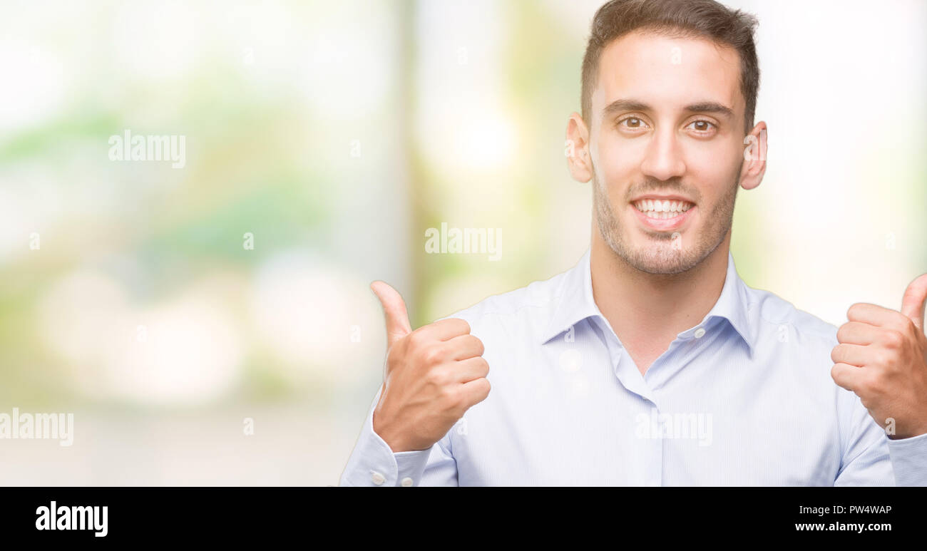 Handsome young businessman success sign doing positive gesture with ...