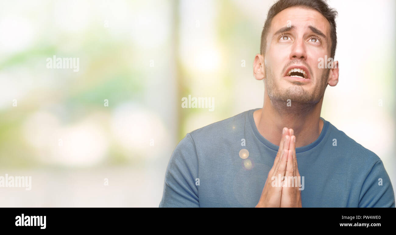 Handsome young casual man begging and praying with hands together with ...