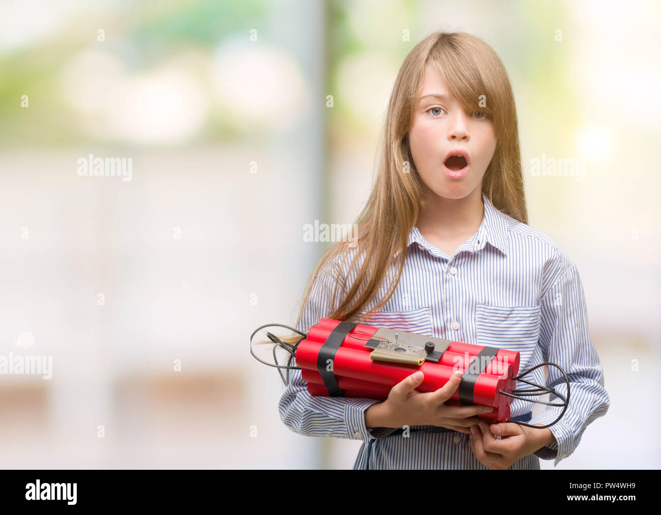 Young blonde child holding dynamite bomb scared in shock with a ...