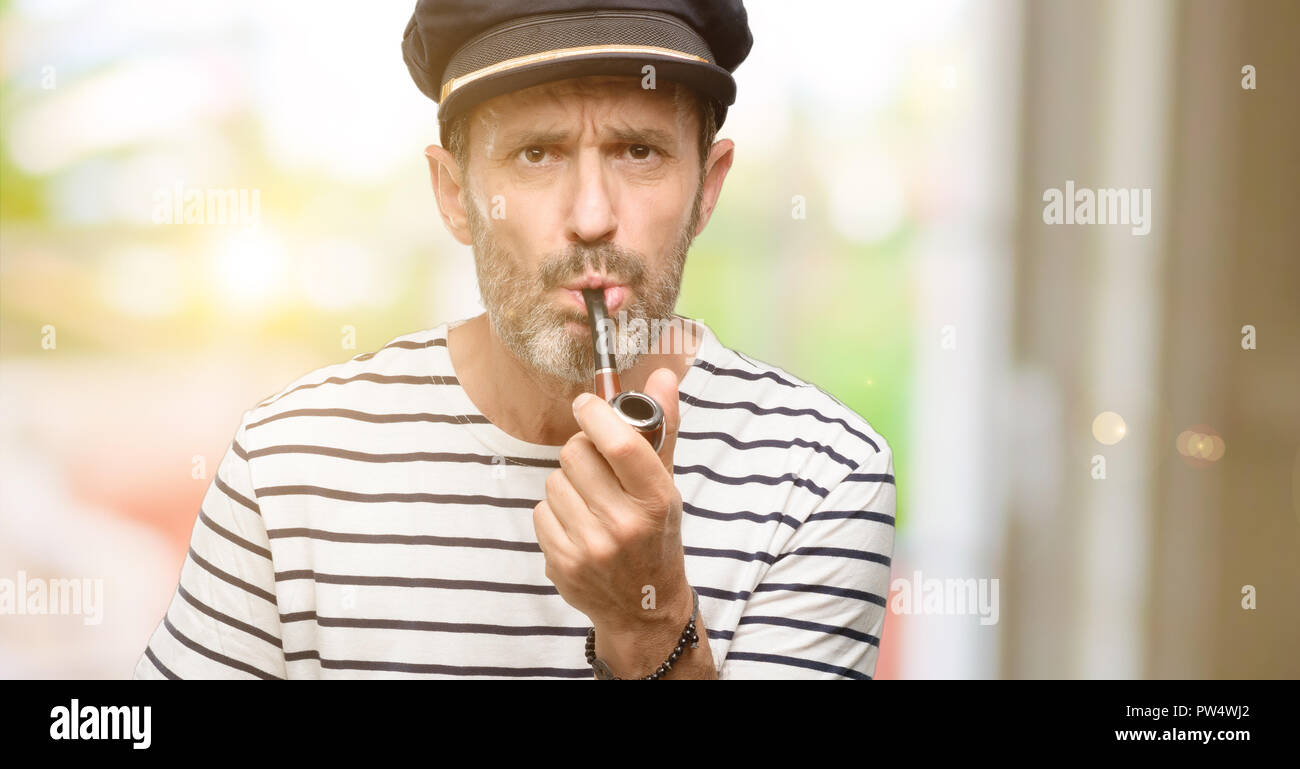 Sailor captain man smoking a tobacco pipe scared in shock, expressing ...