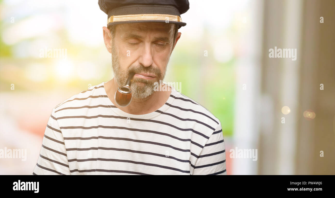 Sailor captain man smoking a tobacco pipe with sleepy expression, being ...