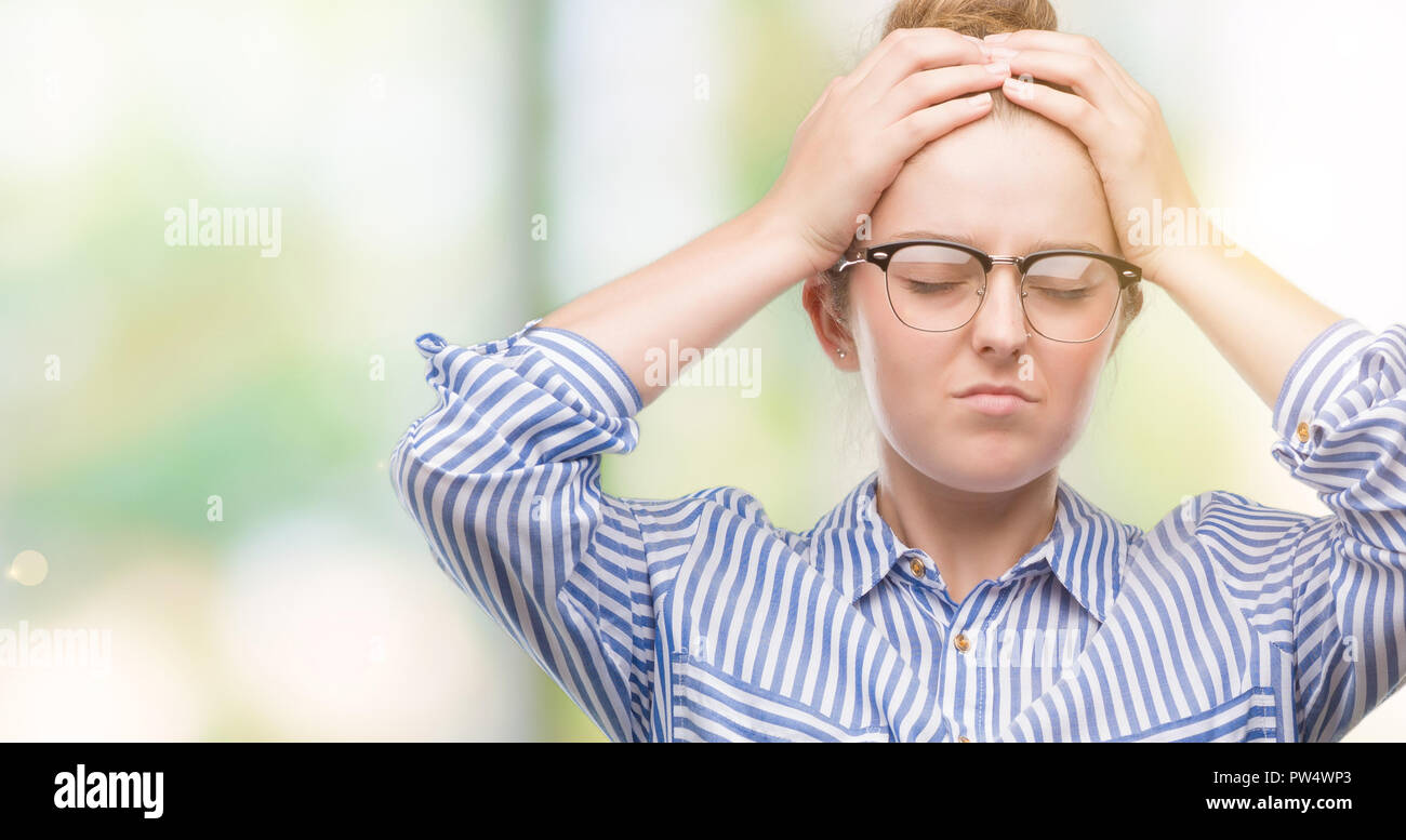 Young blonde business woman suffering from headache desperate and ...