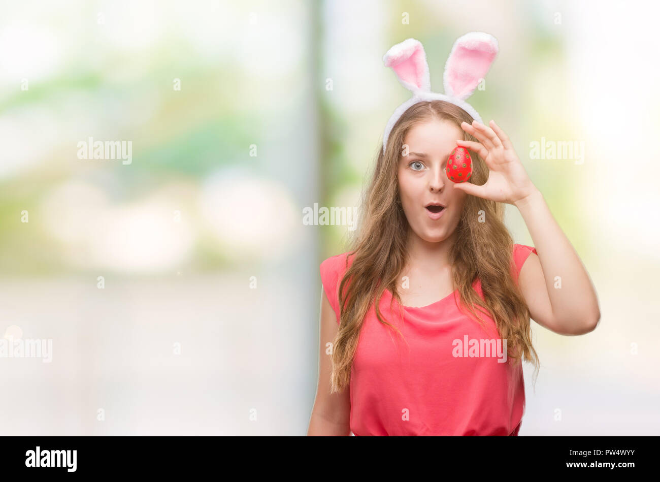 Young blonde woman wearing easter bunny ears scared in shock with a ...
