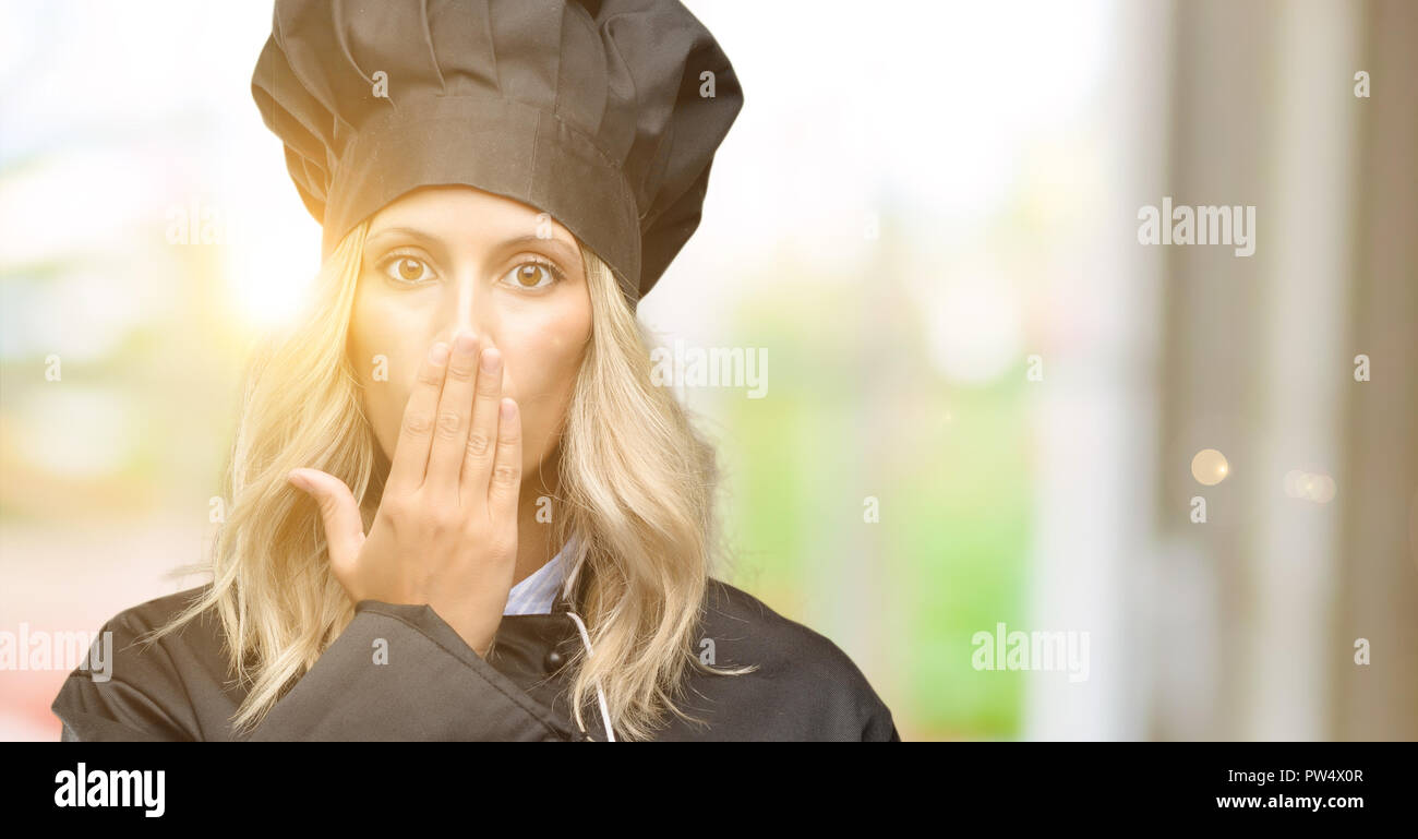 Beautiful cook woman chef covers mouth in shock, looks shy, expressing ...