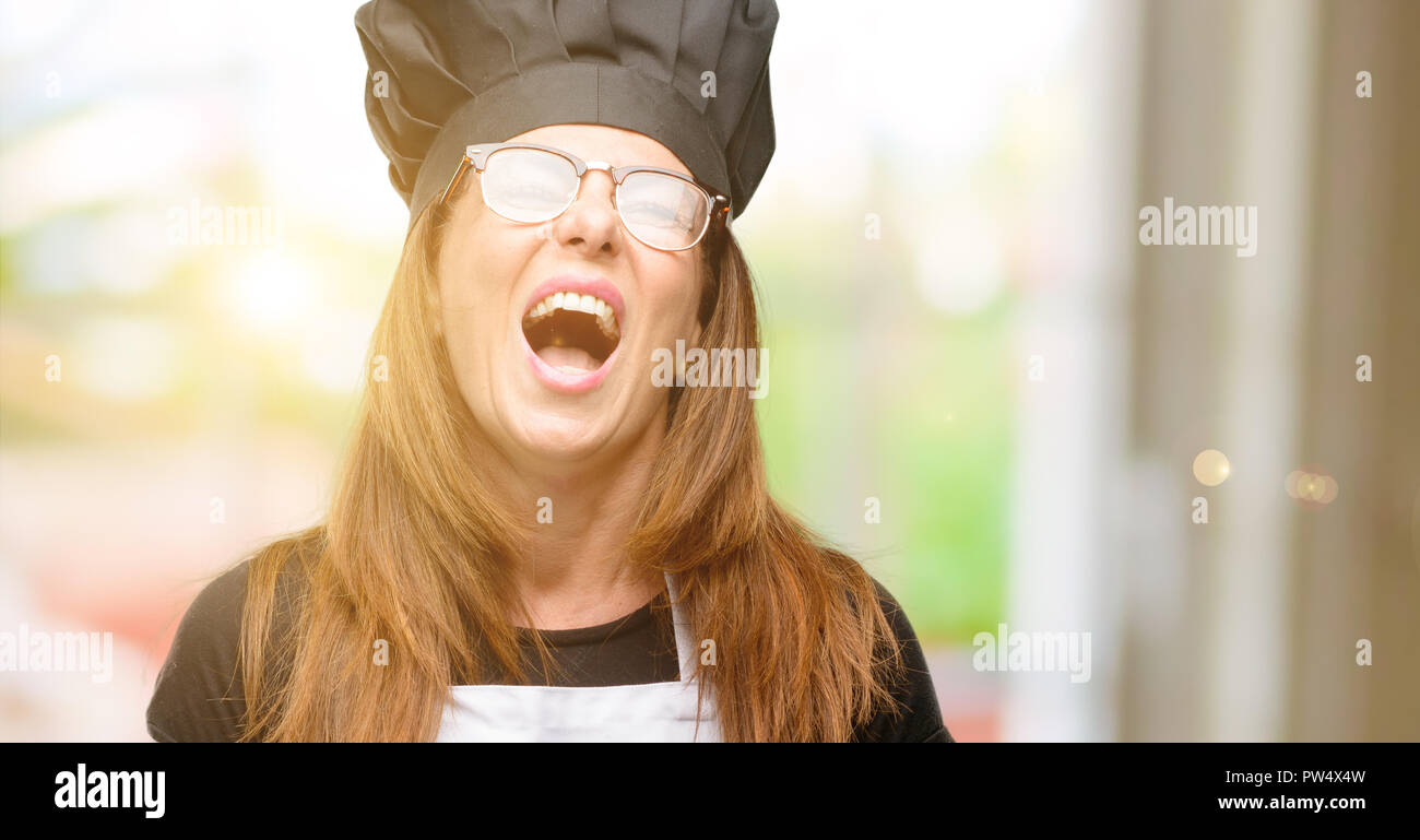 Middle age cook woman wearing chef apron stressful, terrified in panic ...