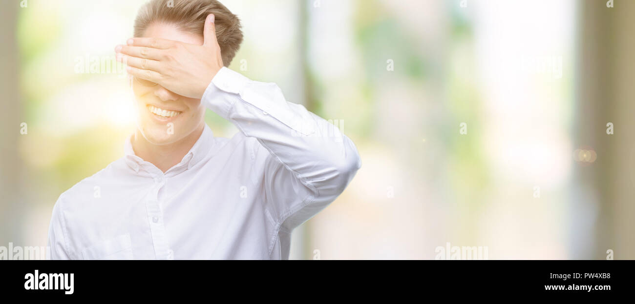 Young handsome blond man smiling and laughing with hand on face ...