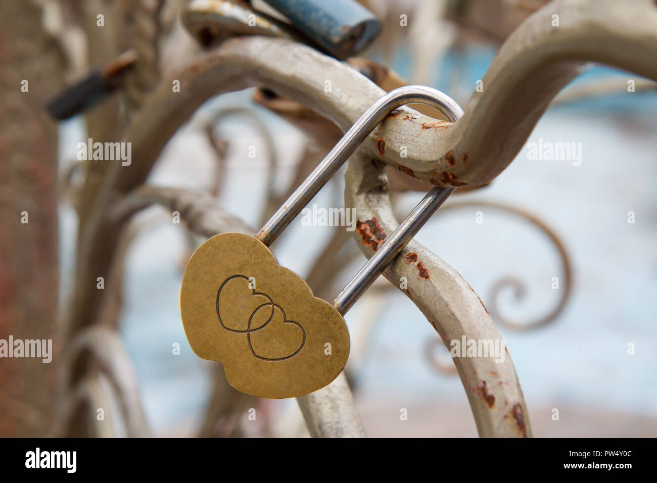 Padlock with engraving of two hearts on metal tree. Selective focus on ...