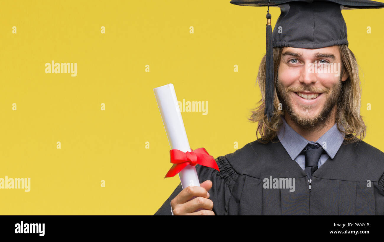 Young handsome graduate man with long hair holding degree over isolated ...