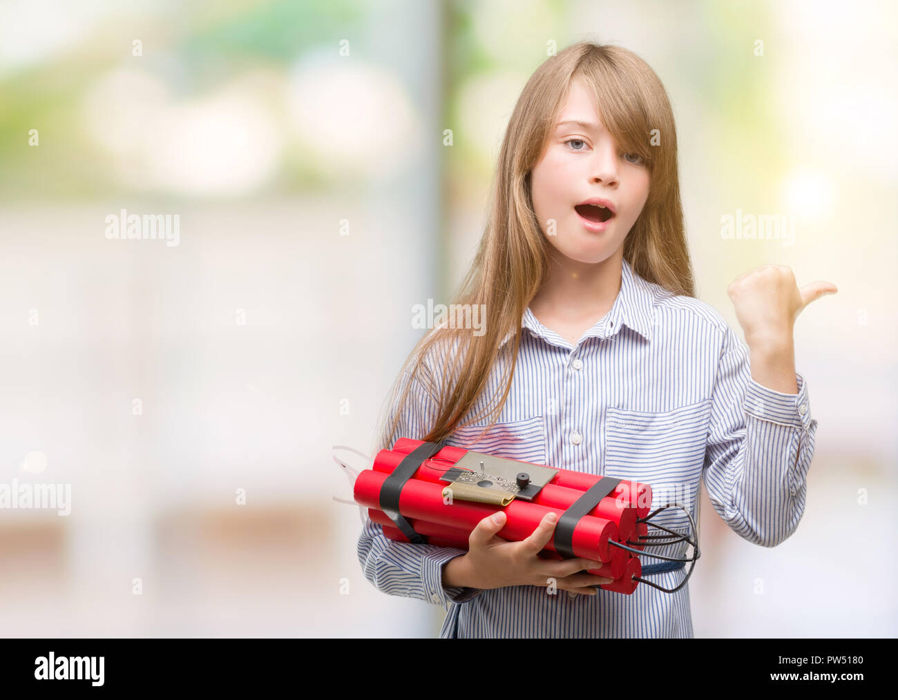 Young blonde child holding dynamite bomb pointing with hand and finger ...