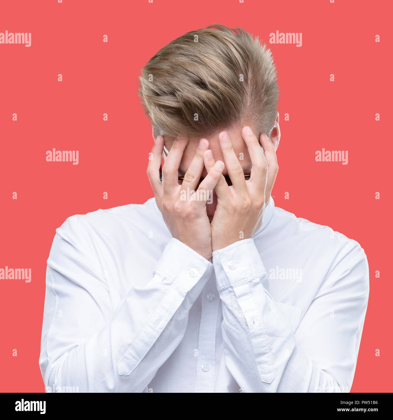 Young handsome blond man with sad expression covering face with hands ...