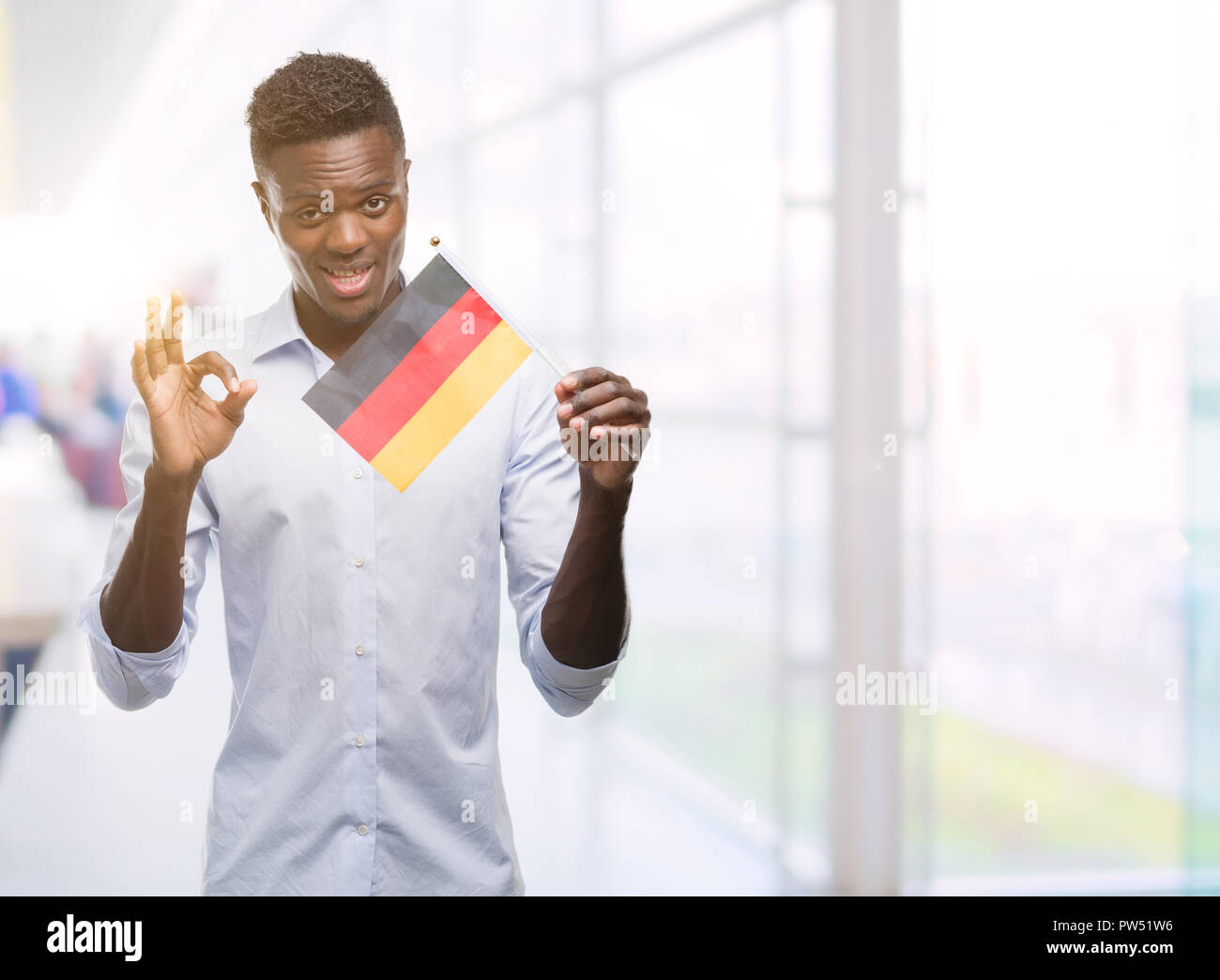 Young african american man holding german flag doing ok sign with ...
