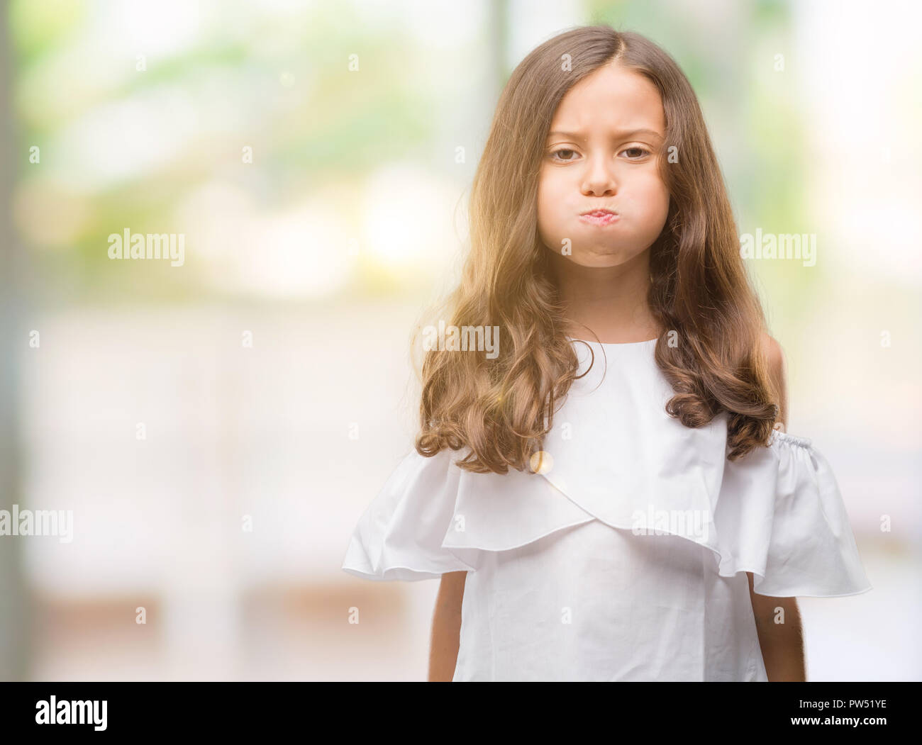 Brunette hispanic girl puffing cheeks with funny face. Mouth inflated ...