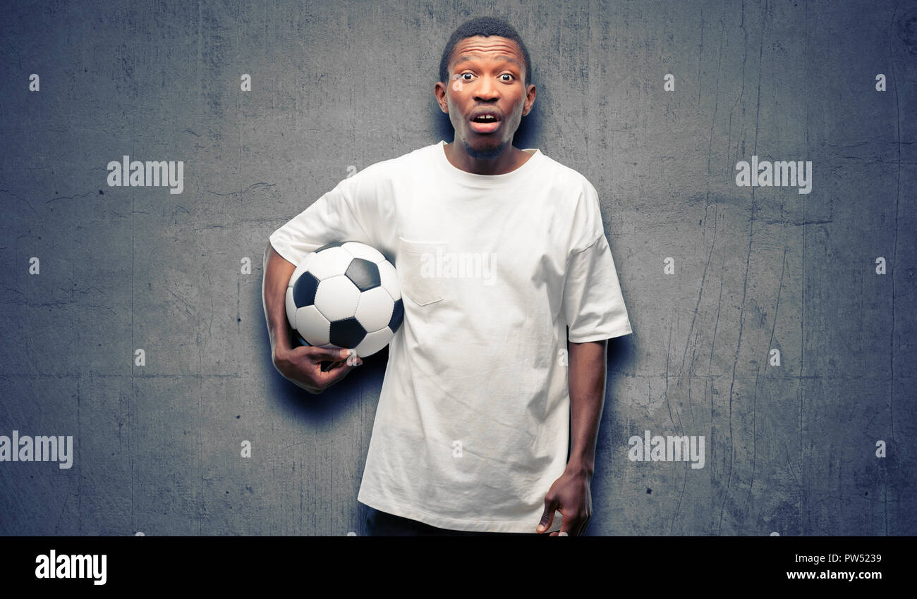 African black man holding soccer ball scared in shock, expressing panic ...
