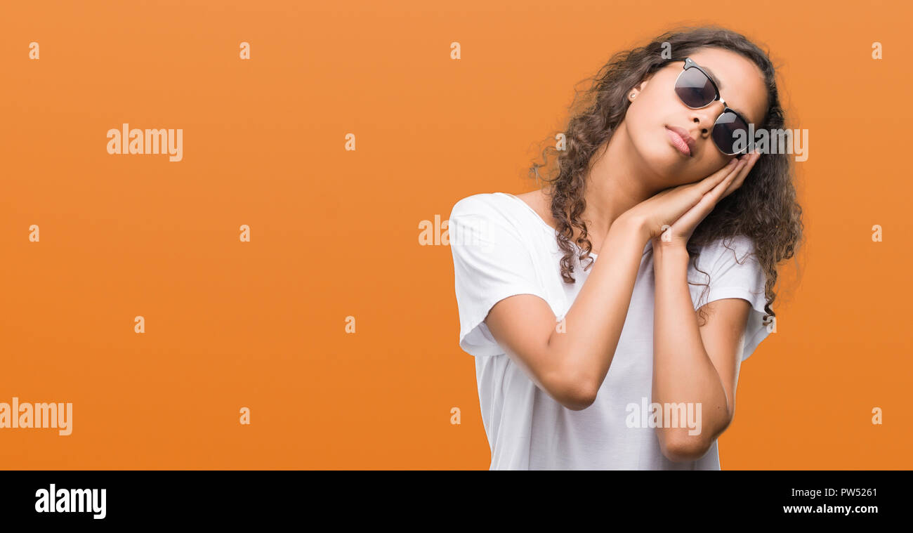 Young hispanic woman wearing sunglasses sleeping tired dreaming and ...