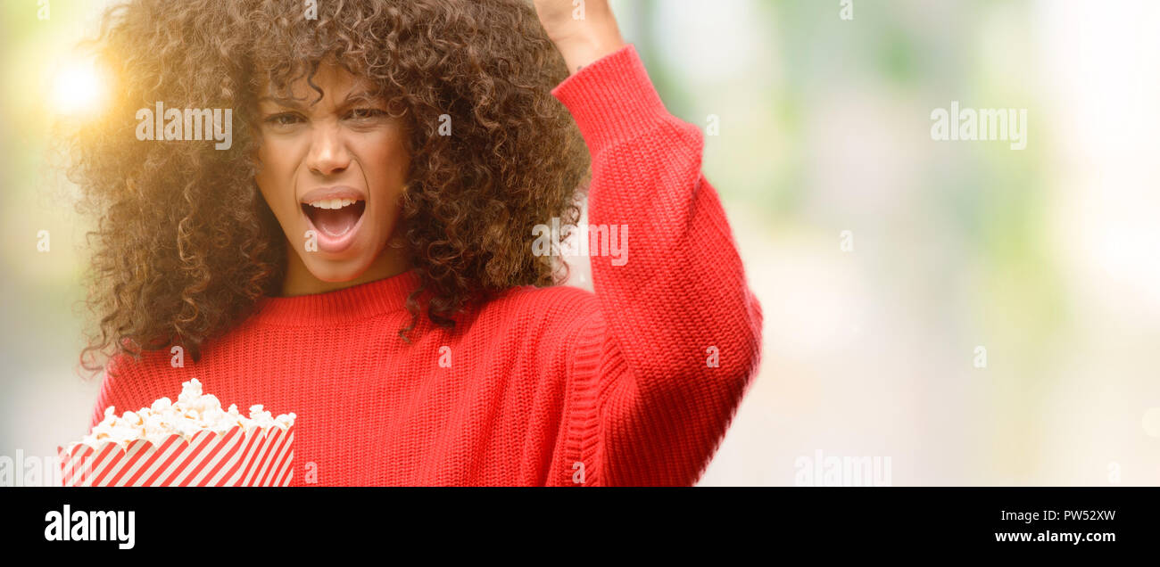 African american woman eating popcorn annoyed and frustrated shouting ...