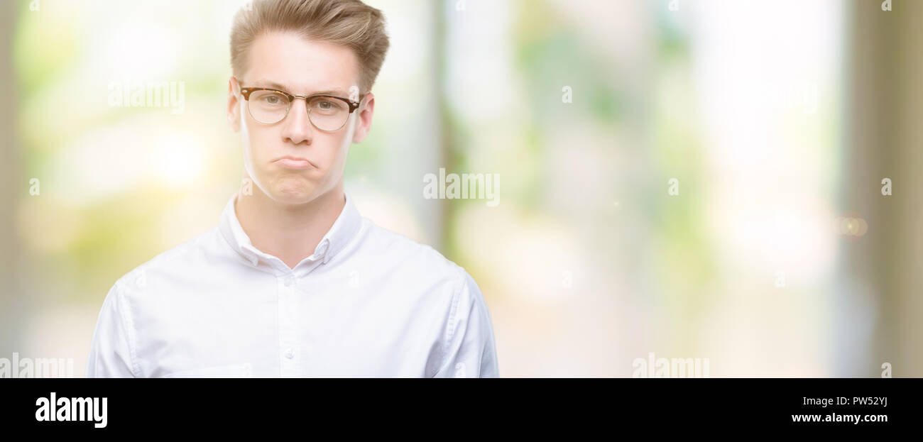 Young handsome blond man depressed and worry for distress, crying angry ...