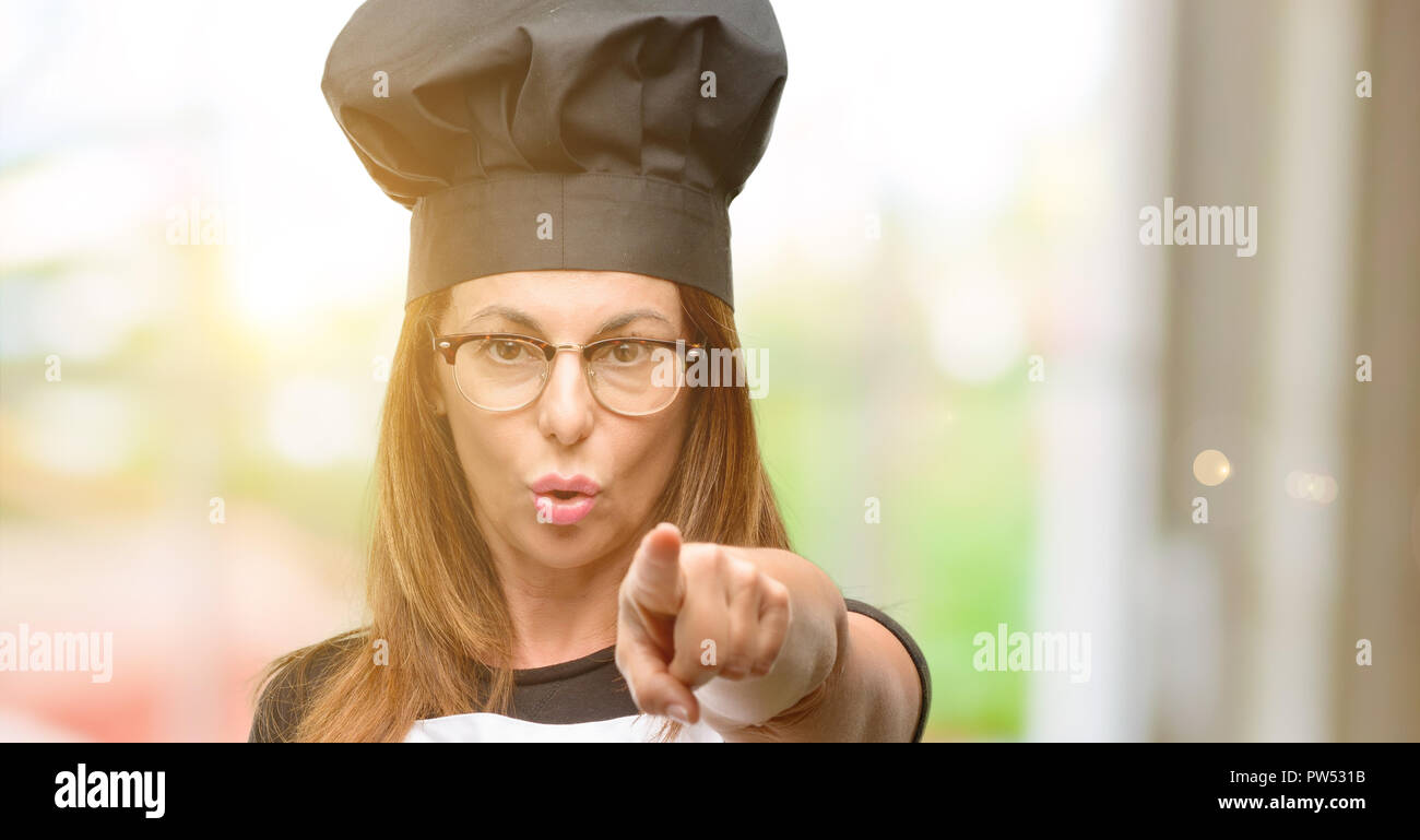 Middle age cook woman wearing chef apron pointing to the front with ...