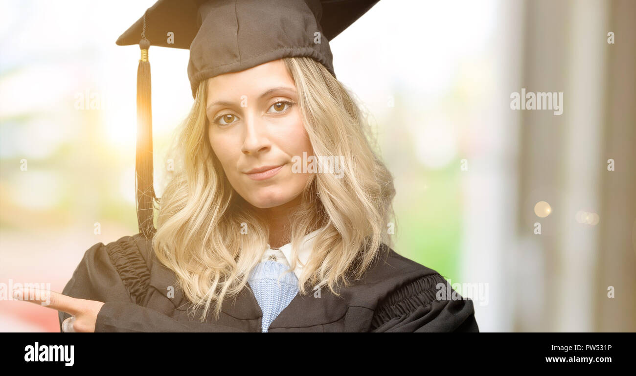 Young graduate woman pointing away side with finger Stock Photo - Alamy