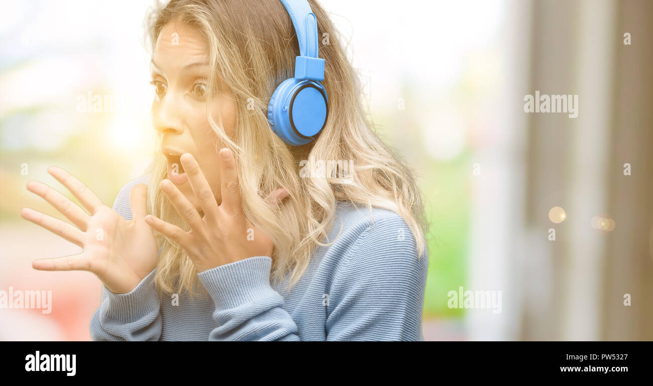 Young beautiful woman listening to music stressful keeping hands on ...