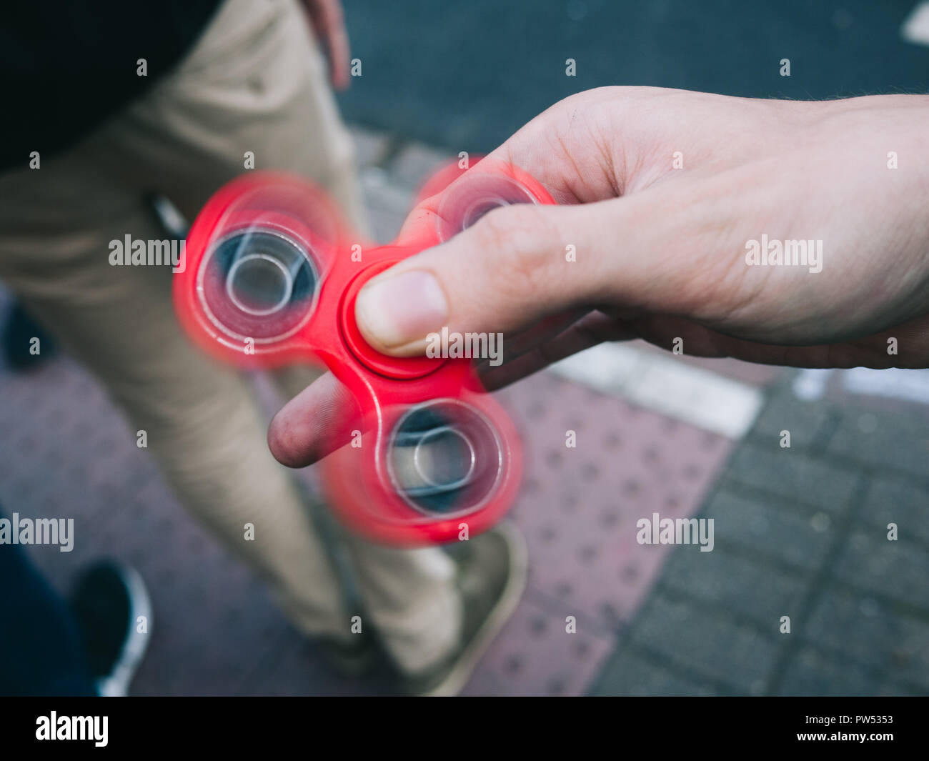 Red fidget spinner spinning in expert hands Stock Photo - Alamy