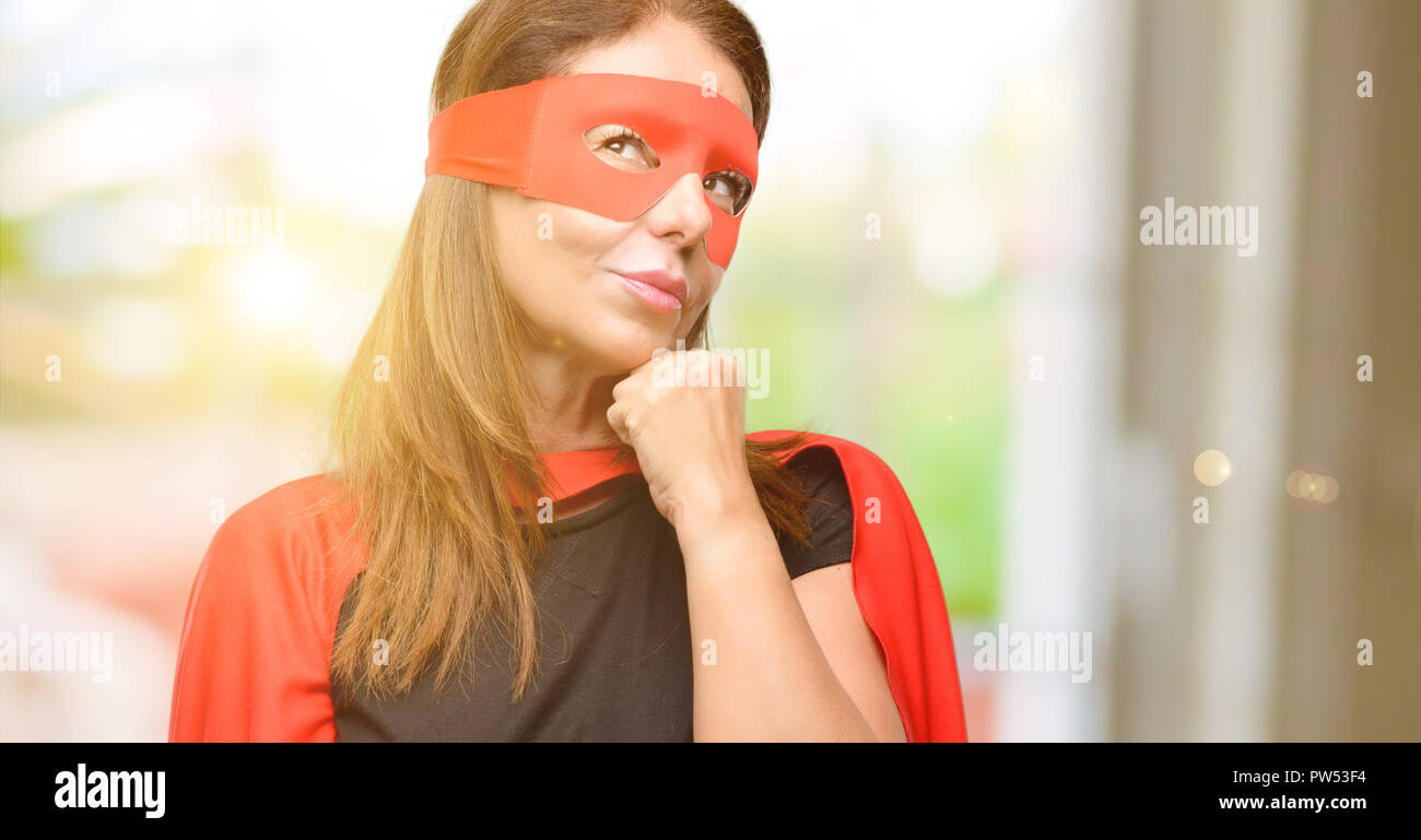 Middle age super hero woman wearing red mask and cape thinking and ...