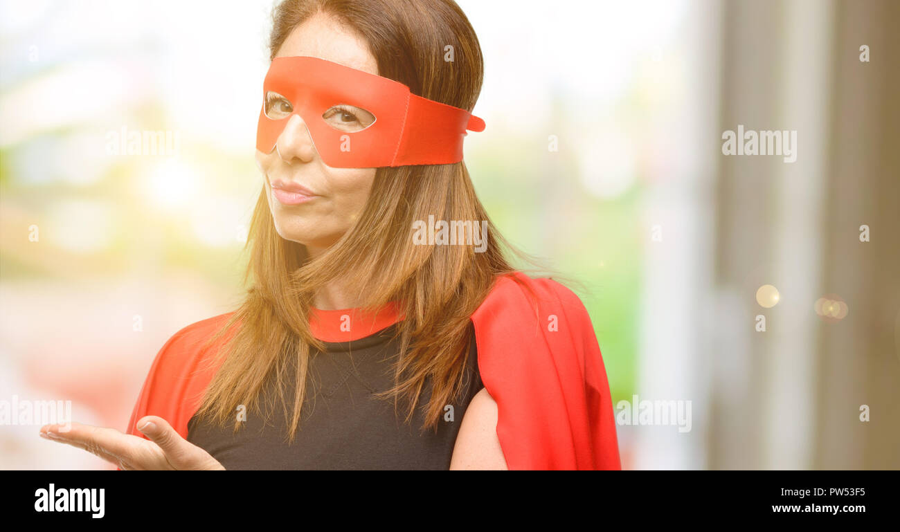 Middle age super hero woman wearing red mask and cape holding something ...
