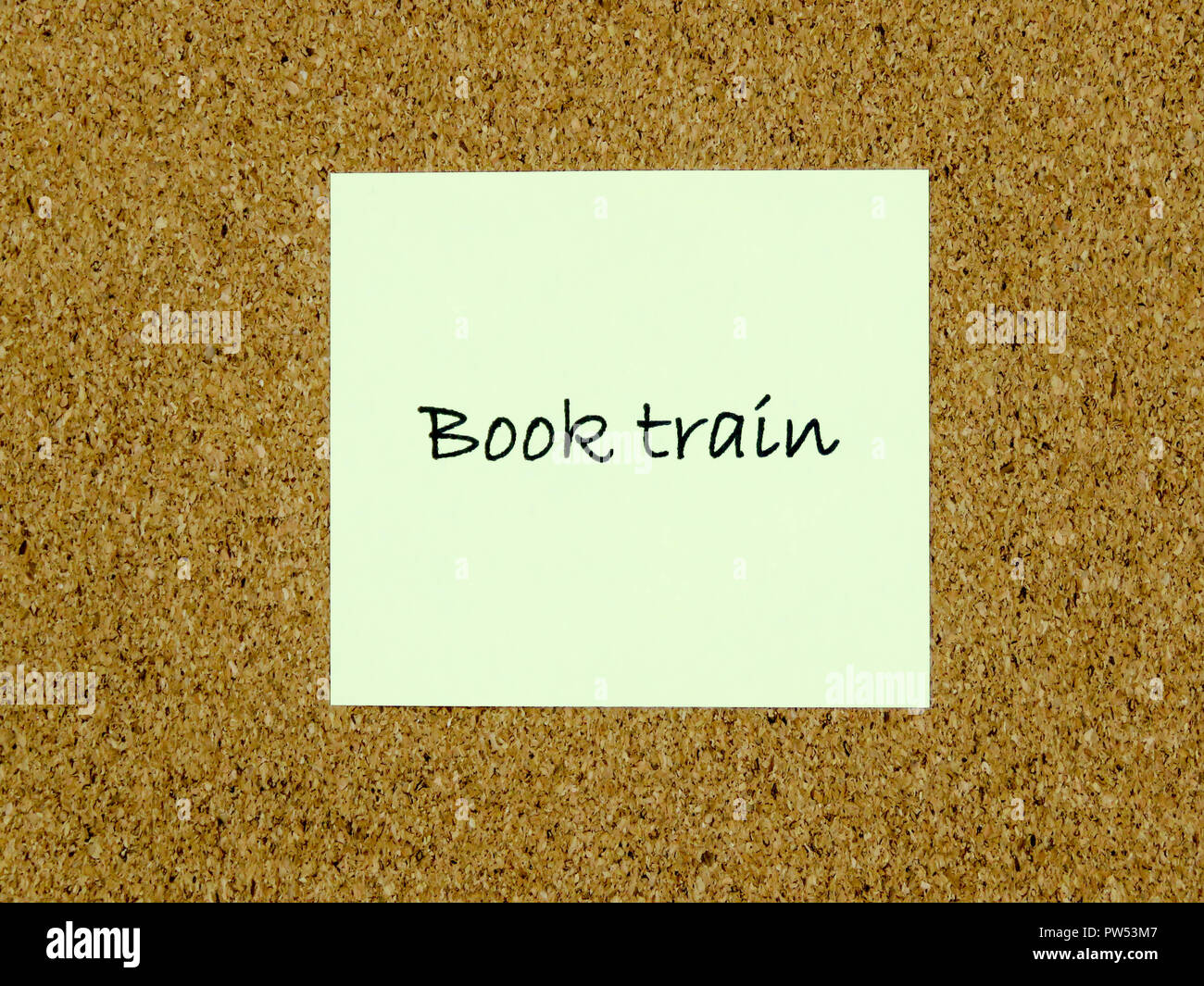 A yellow sticky note with book train written on it on a cork board ...