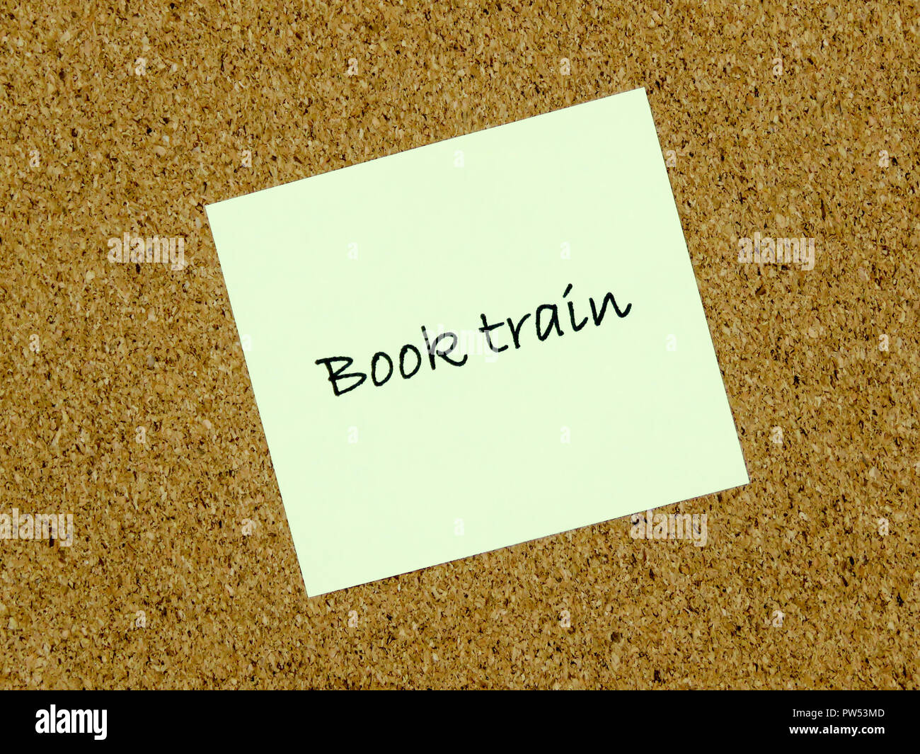 A yellow sticky note with book train written on it on a cork board ...