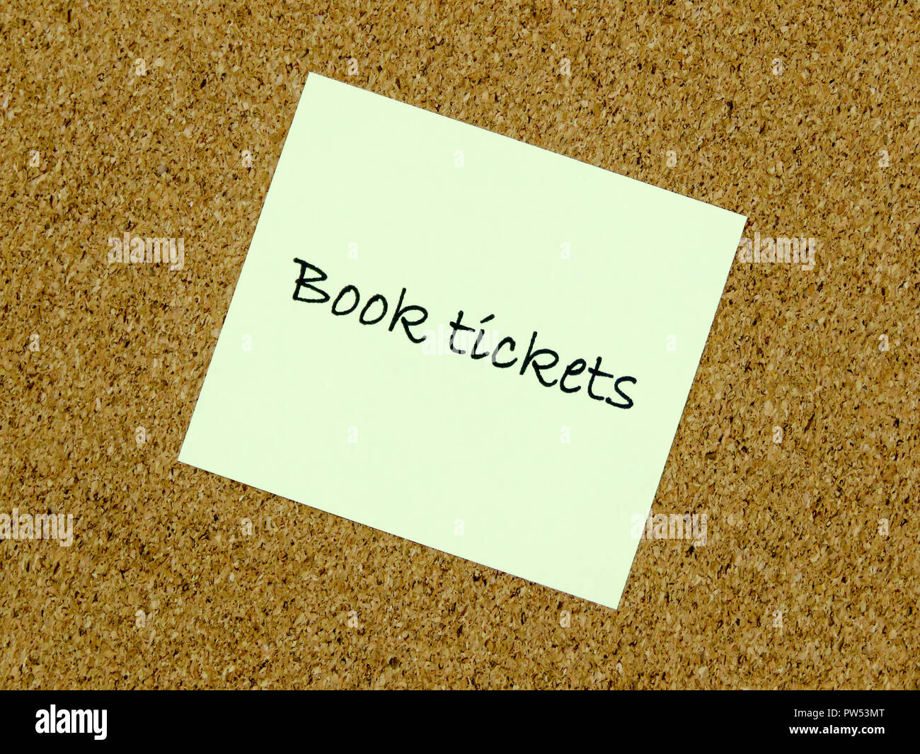 A yellow sticky note with book tickets written on it on a cork board ...