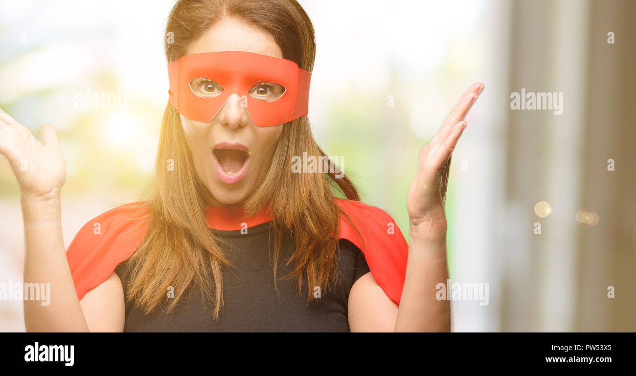 Middle age super hero woman wearing red mask and cape happy and ...
