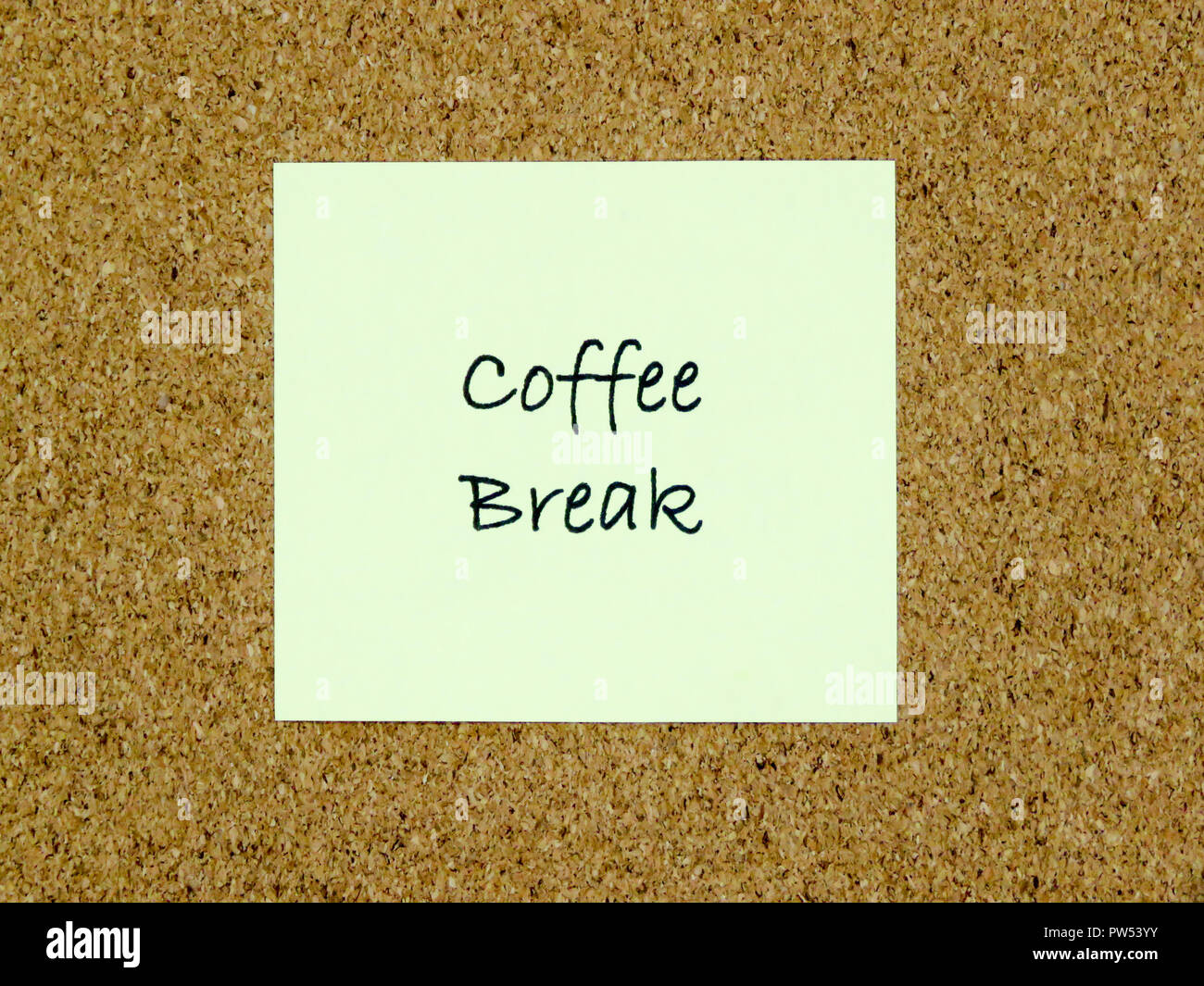 A yellow sticky note with coffee break written on it on a cork board ...