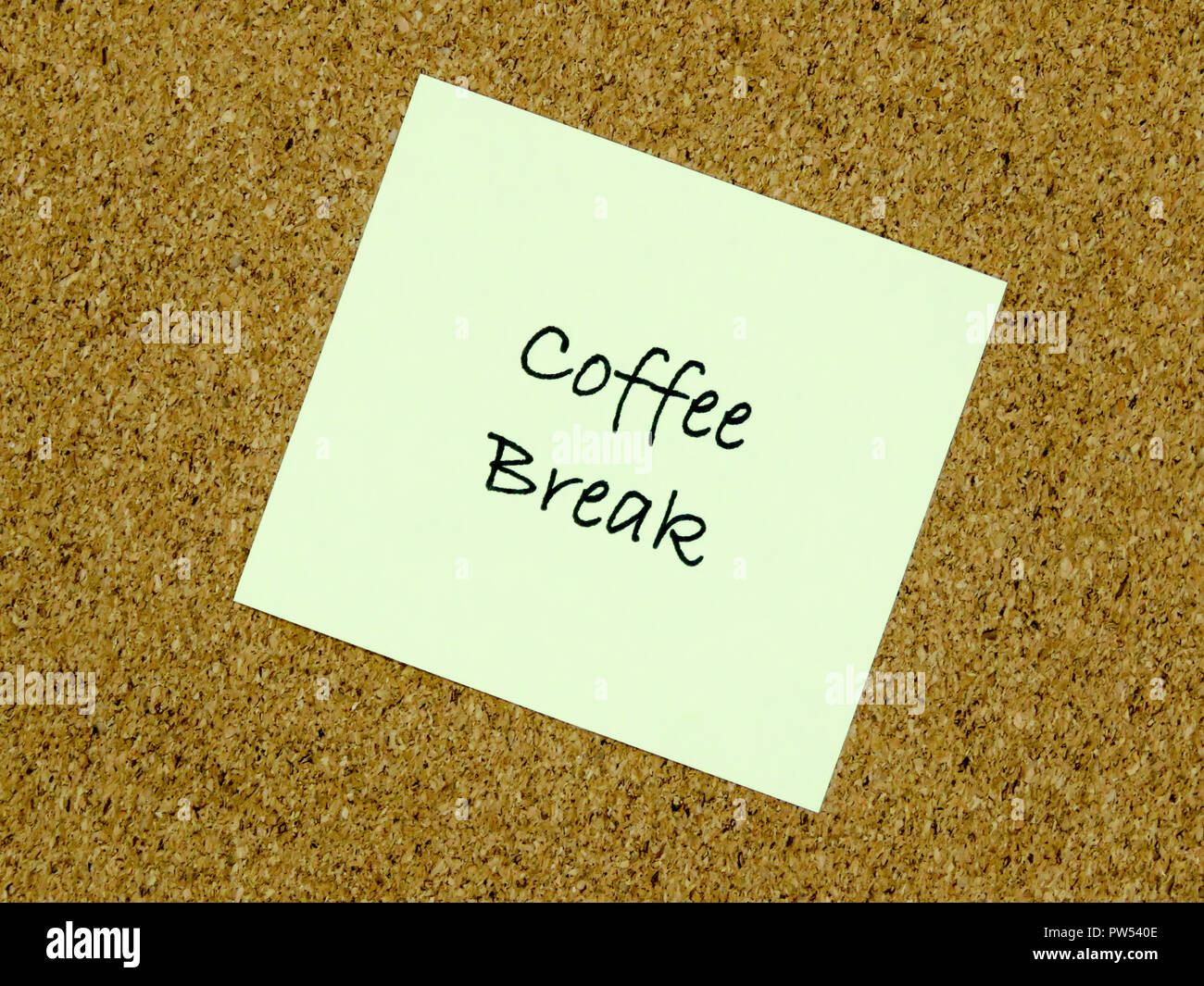 A yellow sticky note with coffee break written on it on a cork board ...
