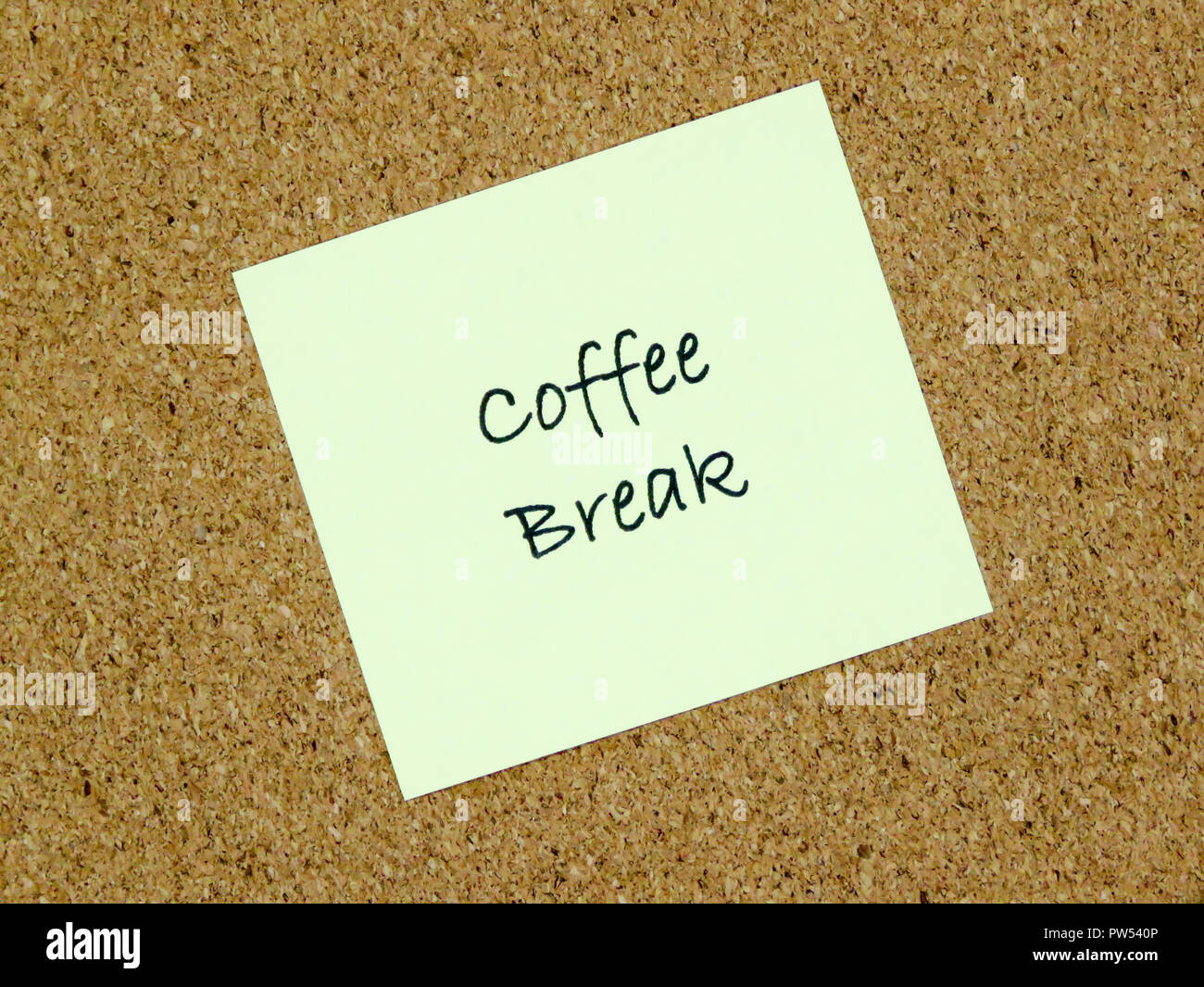 A yellow sticky note with coffee break written on it on a cork board ...