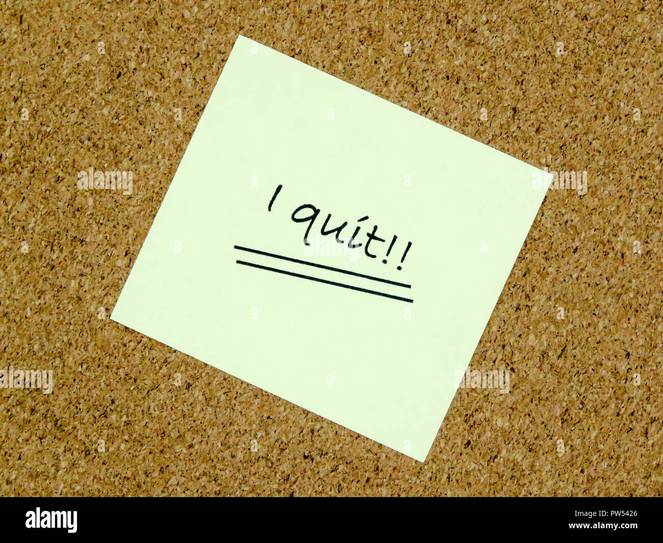 A yellow sticky note with I quit written on it on a cork board ...