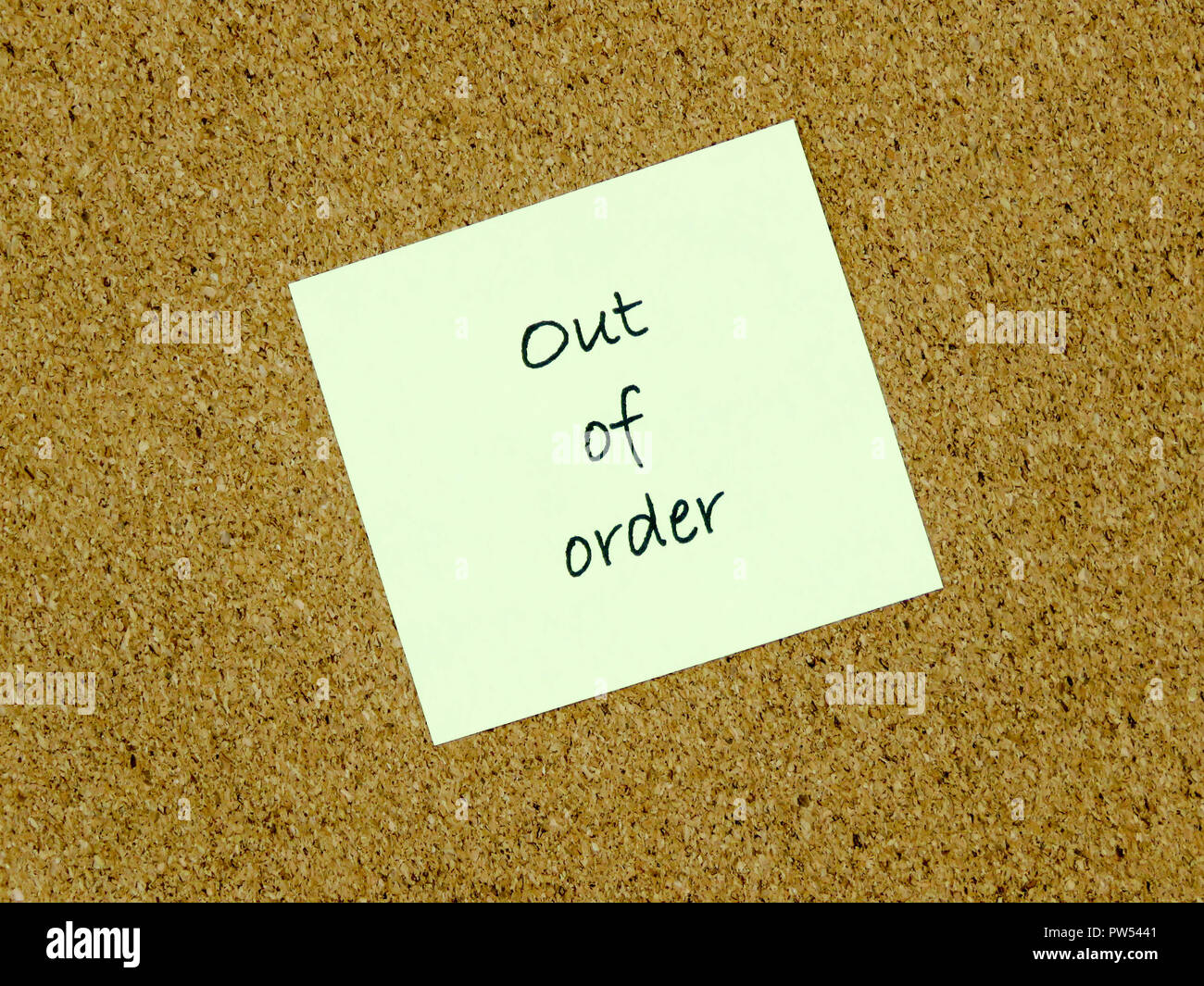 A yellow sticky note with out of order written on it on a cork board ...