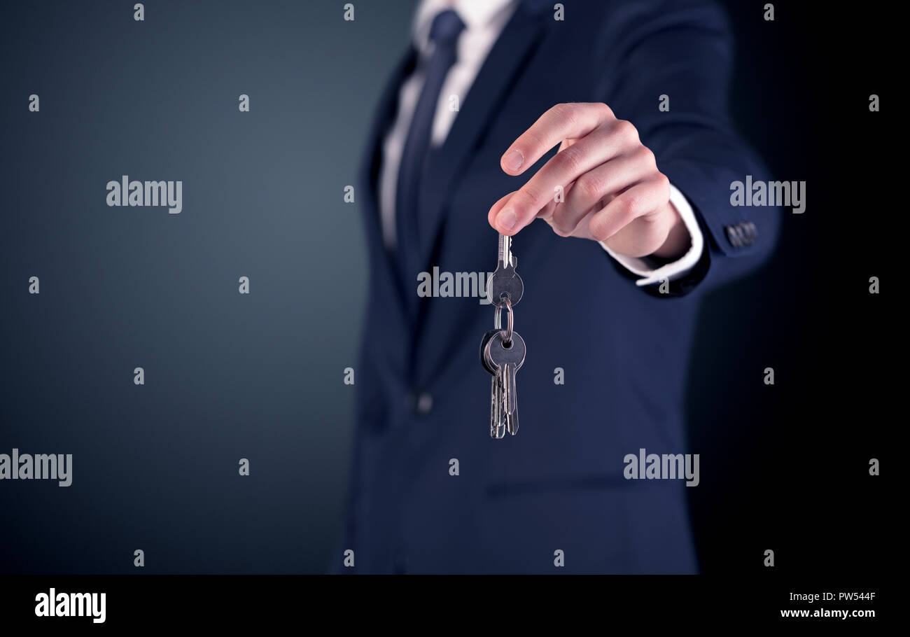 Young businessman hand over keys with empty dark background Stock Photo ...